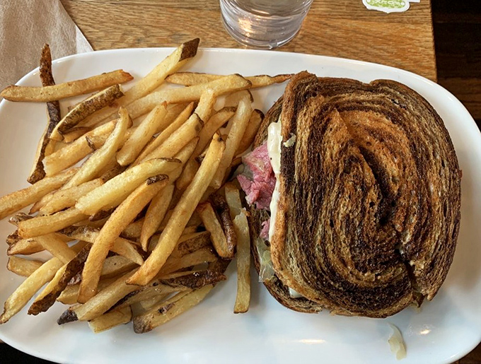 A perfectly grilled Reuben sandwich with a mountain of fries &ndash; the kind of lunch that demands a nap afterward but is entirely worth the sacrifice.