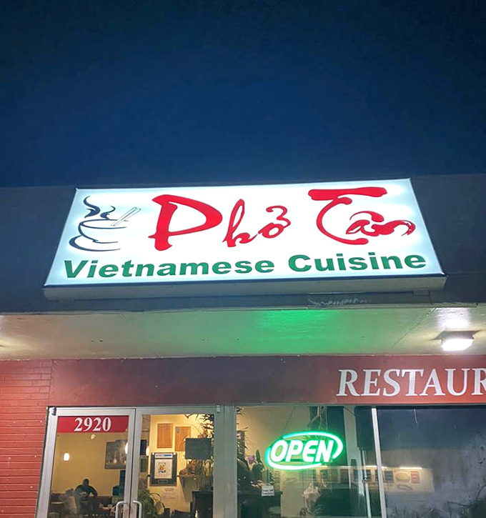 The illuminated sign glows like a beacon in the night. A lighthouse for hungry souls seeking authentic Vietnamese flavors.