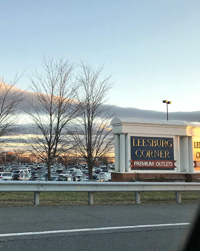 The "Leesburg Corner" sign catches golden hour light, standing sentinel at the gateway to what many consider the eighth wonder of the retail world.