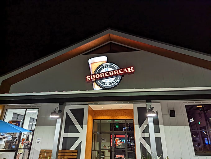 The Shorebreak sign glows like a lighthouse for hungry travelers. At night, it transforms from casual eatery to dining destination with just a flip of a switch.