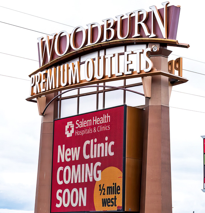 The iconic Woodburn Premium Outlets sign stands tall, beckoning bargain hunters like a retail lighthouse guiding ships to shore.