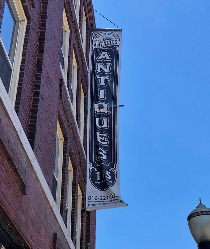 The vertical "ANTIQUES" sign stands as a sentinel against the blue Kansas City sky, guiding treasure hunters to their destination at 115 West 5th Street.