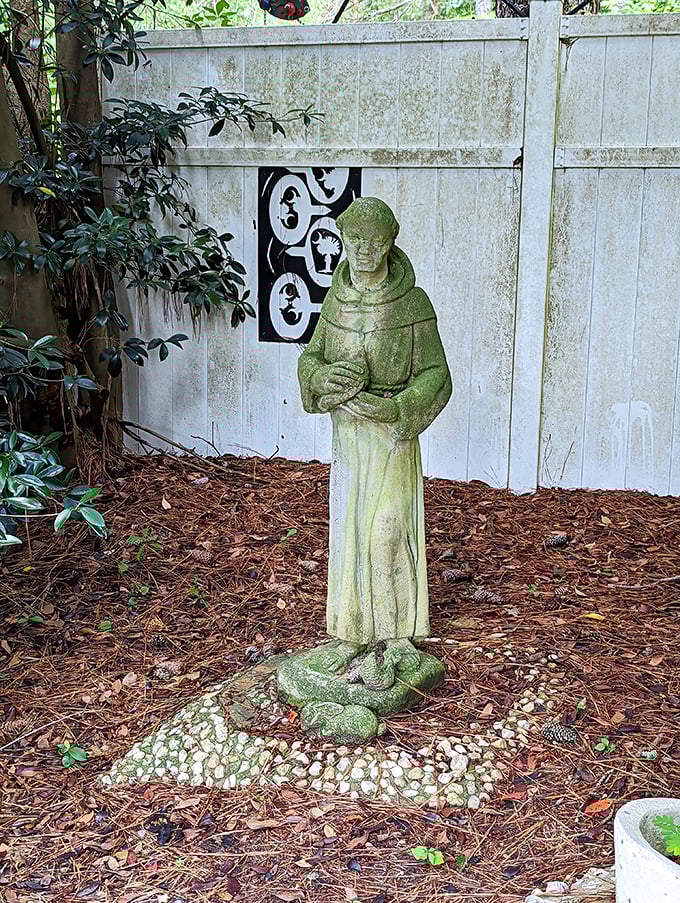 A moss-dusted statue stands sentinel among the plantings. This peaceful figure seems right at home among Pearl's living artworks, adding another layer to the garden's story.