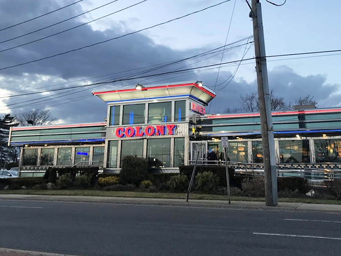 The iconic Colony Diner storefront against moody skies&mdash;a stainless steel promise of comfort food that's stood the test of time.