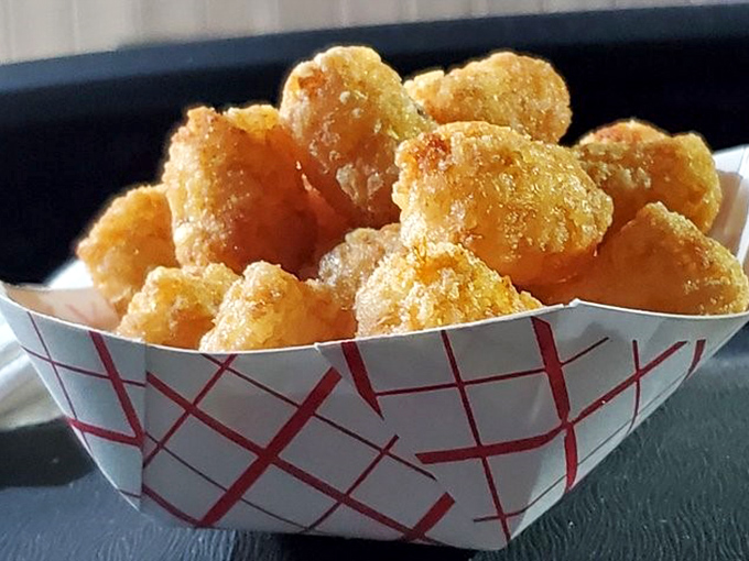 Tater tots that achieve the golden ideal: crispy exterior giving way to fluffy potato goodness, like little nuggets of comfort in a paper boat.