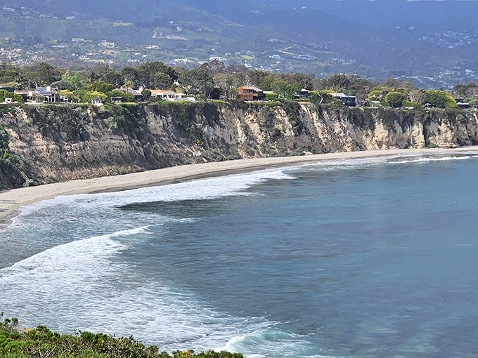 Dramatic cliffs stand guard over a perfect crescent beach, showcasing California's coastline in a view that has launched countless postcards and desktop backgrounds.