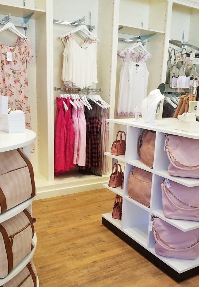 Handbags stand at attention beside summer dresses&mdash;a boutique corner where style meets function in soft pastel harmony.
