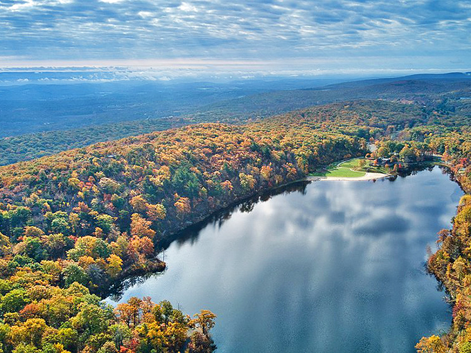 An aerial perspective reveals the park's true magic. From above, Lake Marcia appears as a sapphire nestled in autumn's fiery crown of trees.
