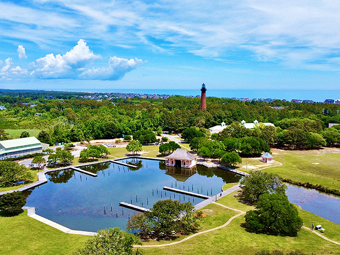 This aerial view reveals the lighthouse's perfect placement within Currituck Heritage Park, surrounded by sound waters and maritime forest.