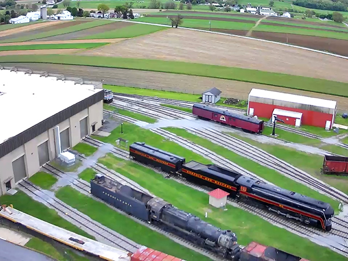 An aerial view reveals the museum's impressive outdoor collection, where massive locomotives rest like sleeping giants on parallel tracks.