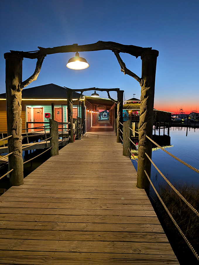 As night falls, the wooden walkway becomes a lantern-lit path to seafood paradise, like something from a coastal fairy tale.