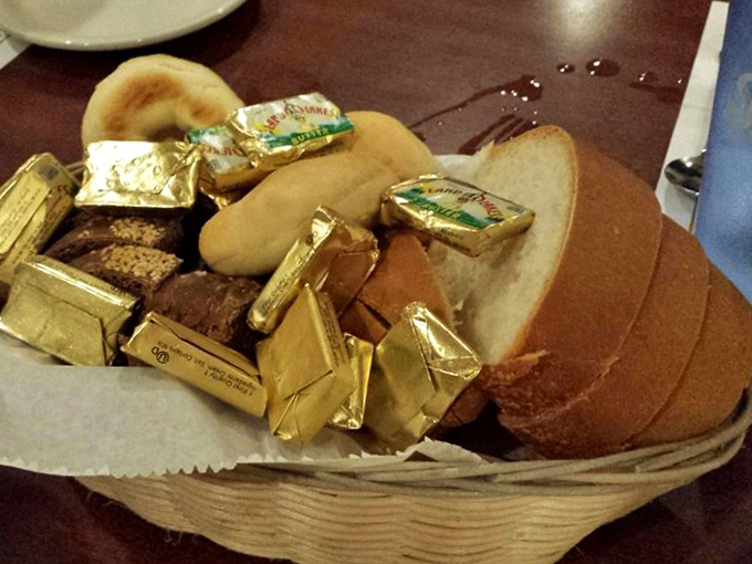 The bread basket&mdash;where butter packets nestle among rolls like golden treasure, because every great meal begins with good bread and anticipation.