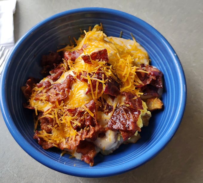 This hearty breakfast bowl loaded with potatoes, eggs, bacon, and cheese is what morning dreams are made of—comfort in a blue ceramic hug.