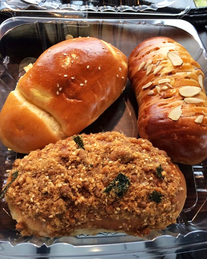 A trio of buns showcasing Sweet Hut's range&mdash;from simple perfection to almond-topped artistry to savory crumb-coated indulgence.