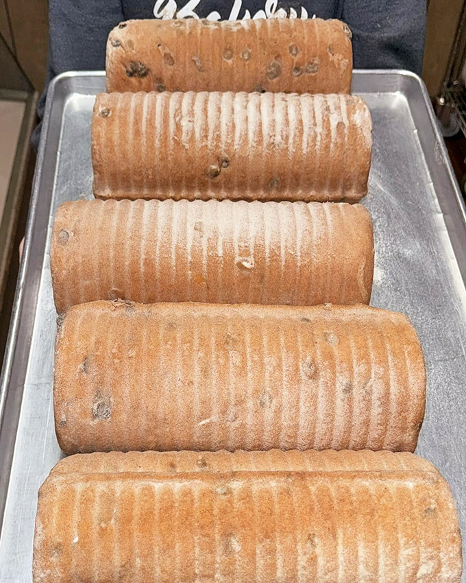Cinnamon raisin bread loaves lined up like edible logs, their ridged exteriors promising swirls of spicy sweetness within.