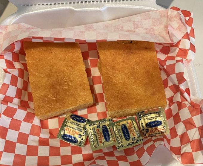 Cornbread squares that strike the perfect balance between sweet and savory, with butter packets standing by for necessary indulgence.