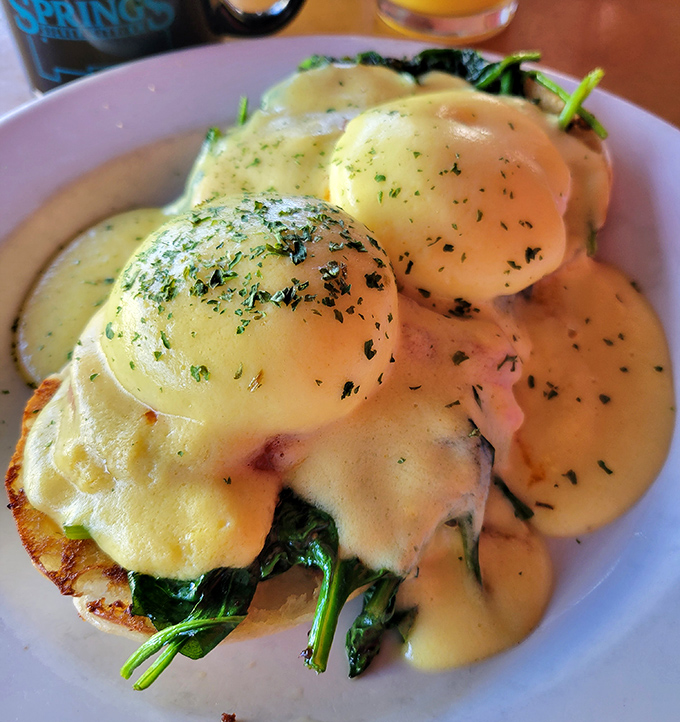 Eggs Benedict that would make a brunch enthusiast weep with joy—perfectly poached eggs nestled on a bed of spinach under hollandaise heaven.