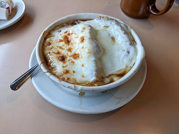 French onion soup wearing its crown of melted cheese like royalty, waiting to be broken into with all the ceremony it deserves.