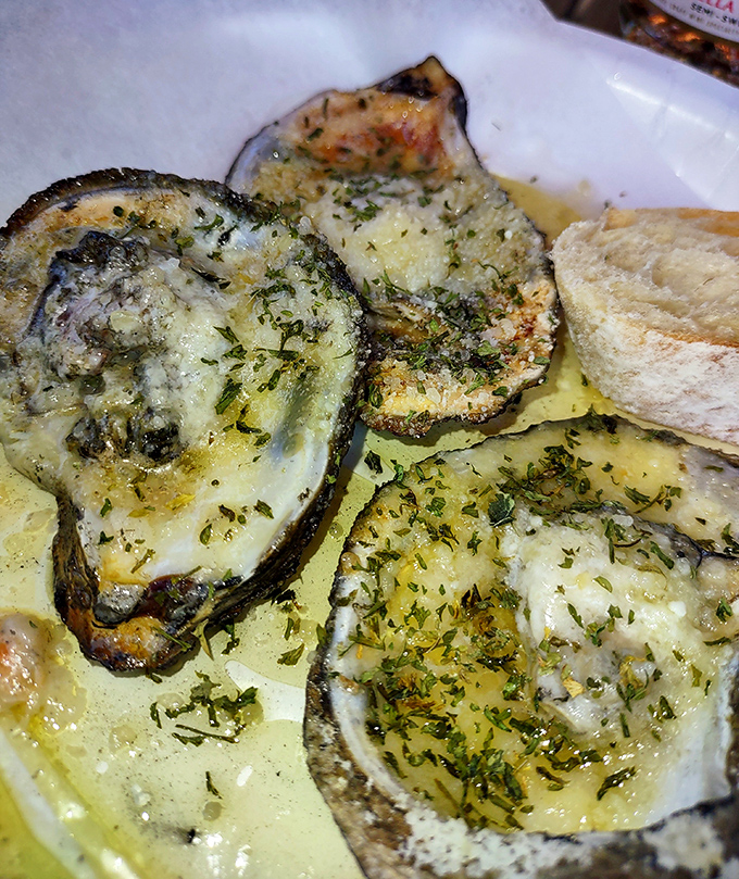 Grilled oysters swimming in garlic butter, proving that sometimes the simplest preparations yield the greatest rewards.