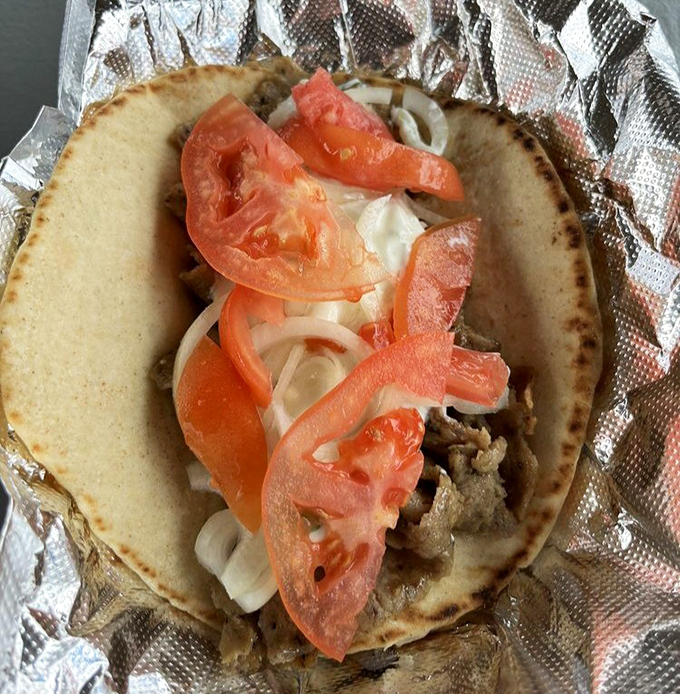 The gyro opens like a delicious book, telling a story of seasoned meat, fresh vegetables, and culinary tradition.