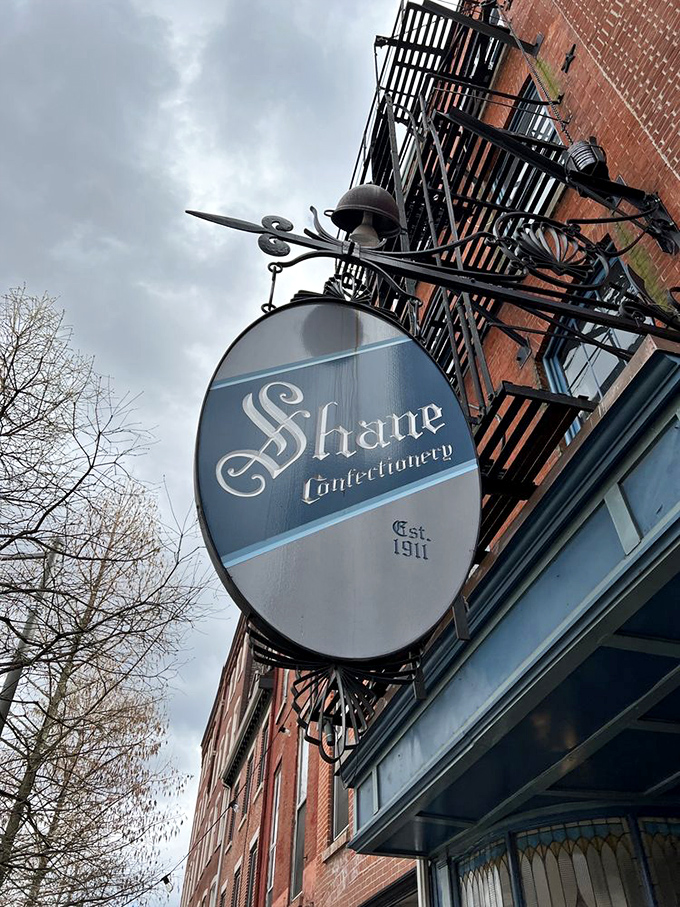 The hanging oval sign swings above Old City like a pocket watch hypnotizing passersby&mdash;"Come in," it whispers, "calories consumed beneath historic signs don't count." 