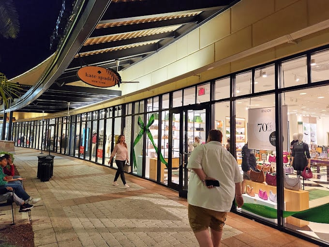 Kate Spade's inviting storefront glows with possibility at twilight, showcasing colorful handbags that practically leap through the windows saying, "Take me home!"