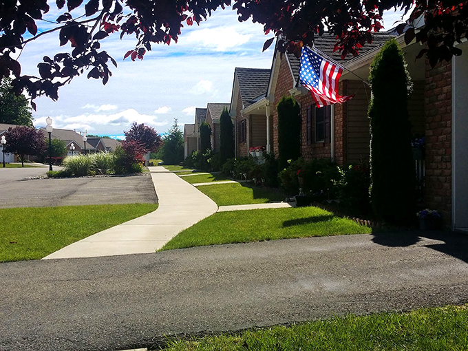 Sidewalks that connect more than just houses. American flags flutter in the breeze along pathways designed for neighborly encounters and daily constitutionals.