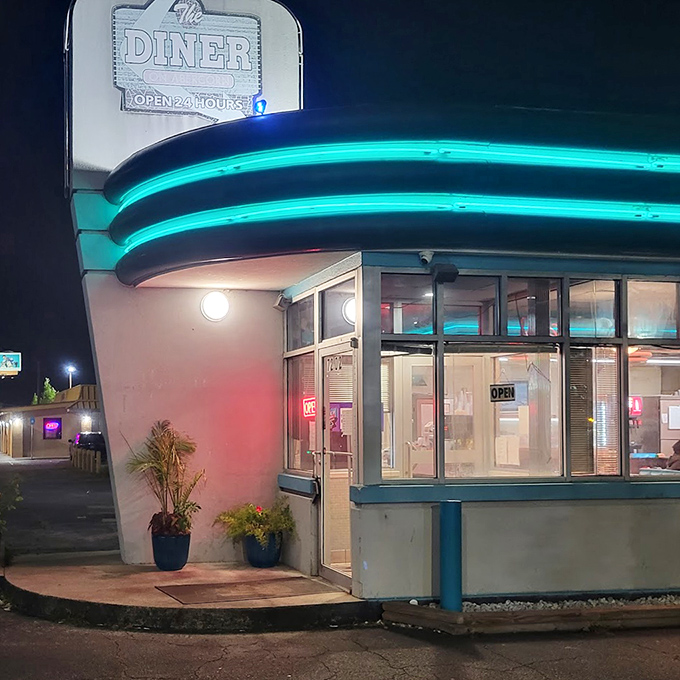 At night, that curved corner entrance with its glowing windows looks like a movie set where the best scene in town is about to unfold.