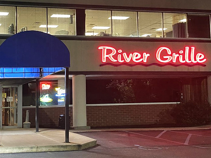 By night, the River Grille sign glows like a neon promise of culinary satisfaction, drawing hungry patrons like moths to a delicious flame.