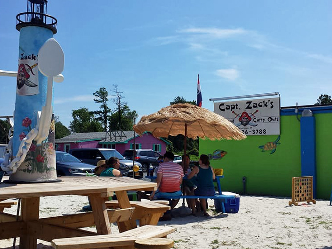 Outdoor seating in the sand with a painted lighthouse watching over—because eating great seafood should feel like a permanent vacation, even on Tuesday.