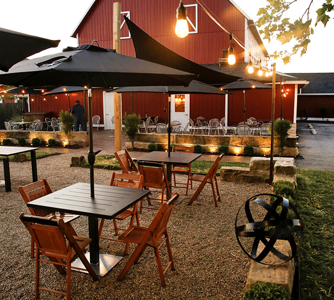 The outdoor seating area transforms into a twinkling oasis at dusk, where string lights and umbrella-shaded tables create the perfect setting for summer evening dining.