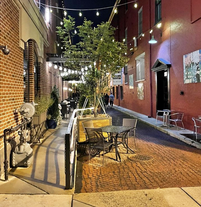 The outdoor seating area, strung with twinkling lights and nestled between historic buildings, turns a simple meal into a magical evening escape.