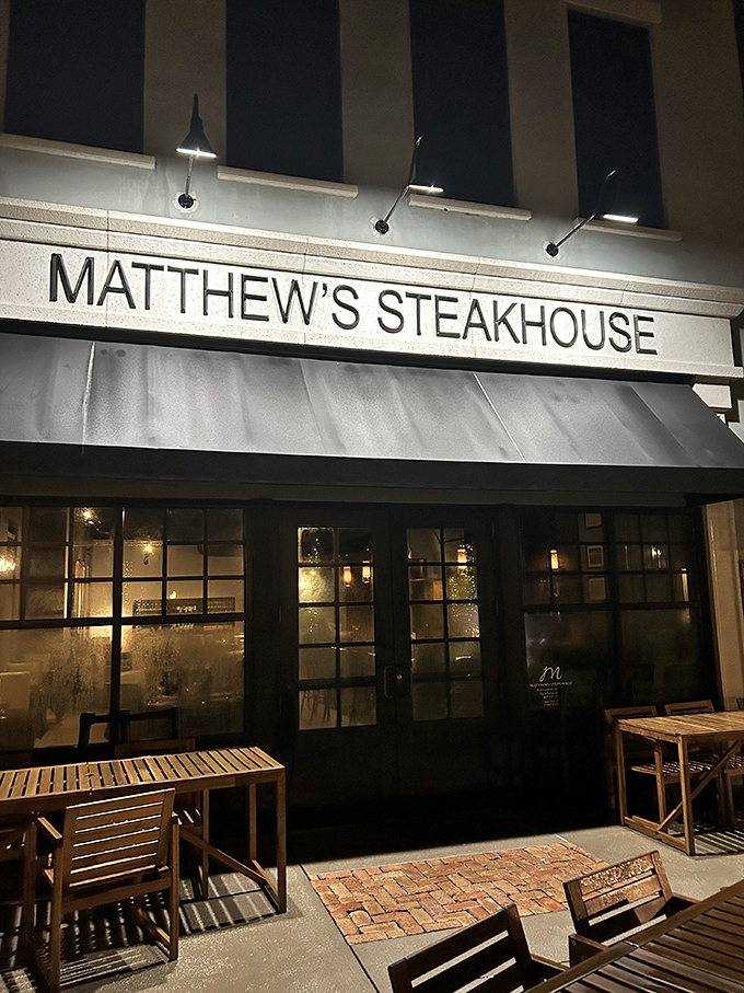 As evening falls, Matthew's Steakhouse glows with invitation, its illuminated sign a beacon for those seeking refuge from ordinary dining experiences.
