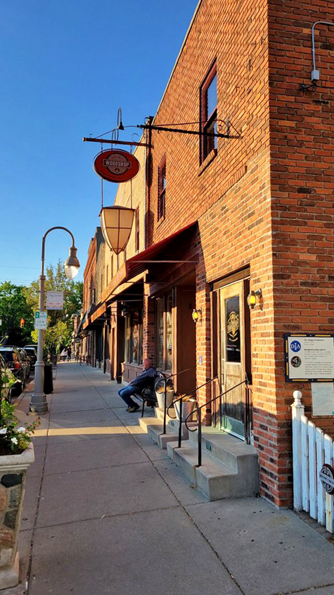 Sunlight bathes the brick exterior in golden hour glow, while a lone figure waits&mdash;proof that patience is indeed a virtue when barbecue is the reward.