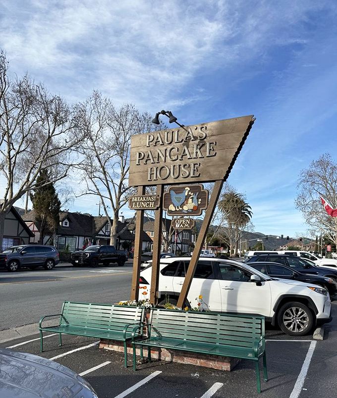 Even the parking area, with its iconic wooden sign and green benches, sets the stage for the Danish experience that awaits just steps away.