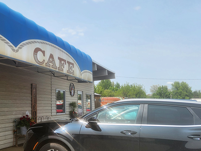 The blue awning and "CAFE" sign announce this roadside haven with the confidence of a place that knows its worth.