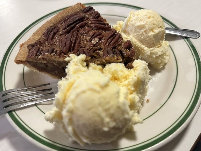 Pecan pie with two scoops of vanilla ice cream—proof that sometimes the best innovation is simply putting two perfect things side by side.