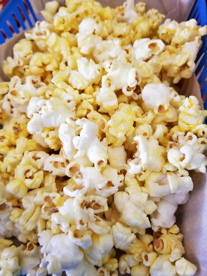 Buttery popcorn served in a blue basket &ndash; the unexpected appetizer that keeps your hands busy while decisions are made.