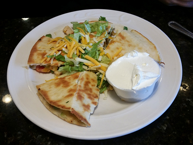 A quesadilla that strikes the perfect balance between crispy exterior and gooey interior, served with a dollop of sour cream for good measure.