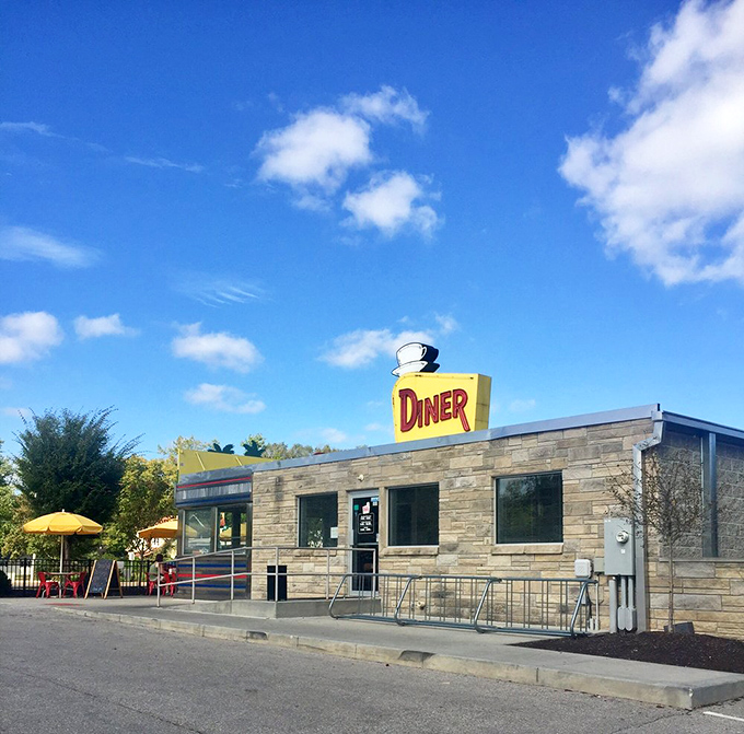 Morning sunshine highlighting the diner's classic profile&mdash;stone meets steel meets neon in an architectural love letter to America's roadside dining heritage.