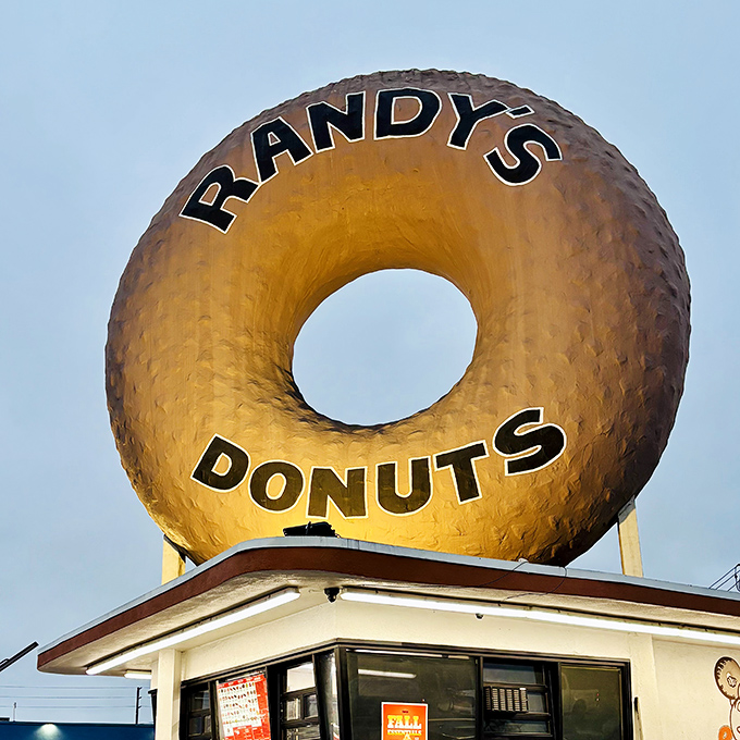As evening approaches, the giant donut glows like a halo in the California sky. A sweet sentinel watching over Inglewood since the 1950s.