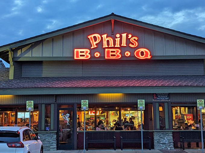 The neon beacon that guides hungry souls home. As evening falls, Phil's BBQ sign glows like a lighthouse, signaling safe harbor for BBQ pilgrims seeking smoky salvation.