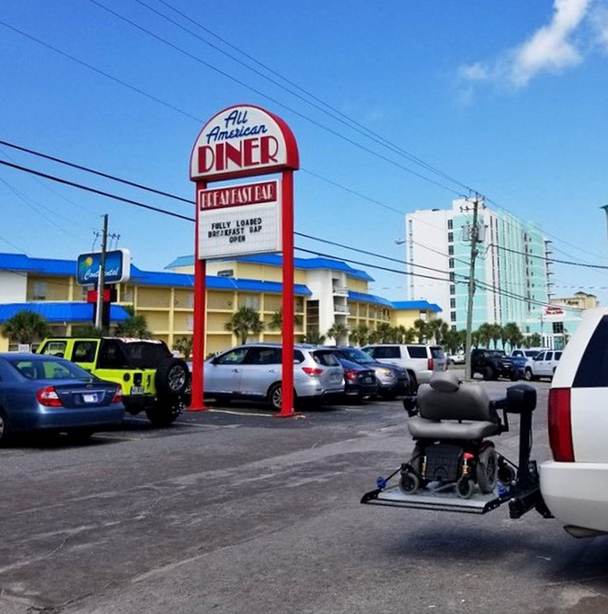 The roadside sign stands tall like a beacon, guiding hungry travelers to breakfast salvation near the beach.