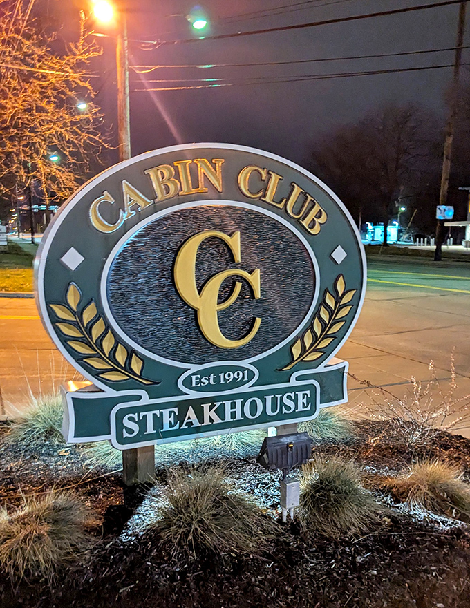 At night, the illuminated Cabin Club sign serves as a beacon for hungry travelers, like a lighthouse guiding ships to safe, delicious harbor.
