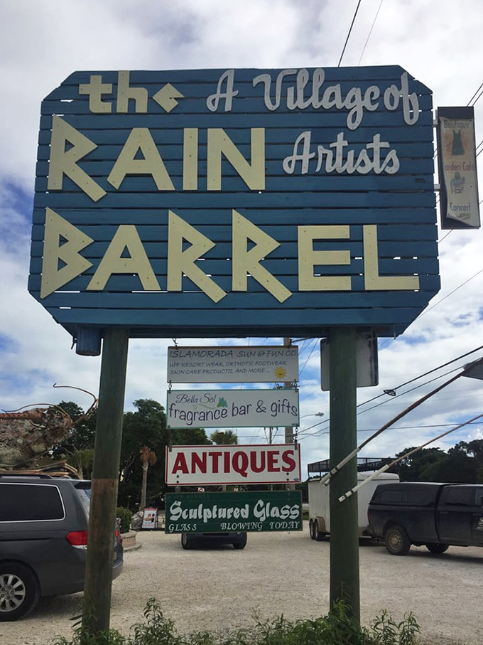 The blue and cream signage announces "A Village of Artists" with the same casual confidence that Jimmy Buffett announces it's 5 o'clock somewhere.