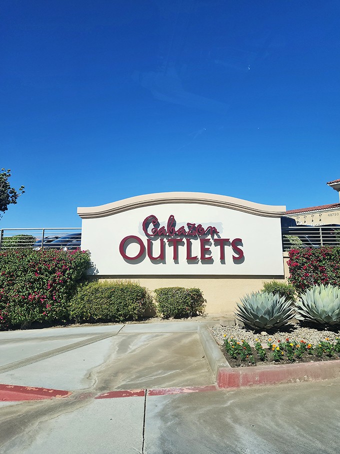 The Cabazon Outlets sign rises from desert landscaping, a beacon of bargains under impossibly blue skies.