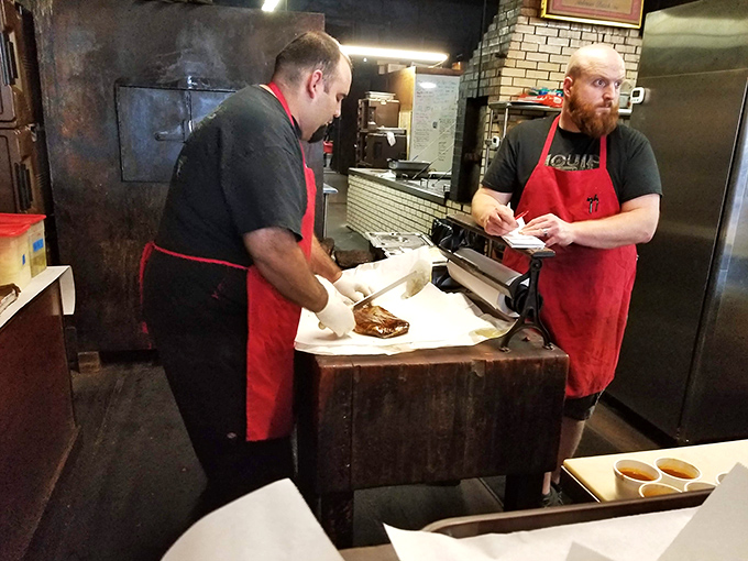 The meat-cutting station&mdash;barbecue's most sacred altar. These red-aproned priests of protein slice with the precision and reverence the meat deserves.