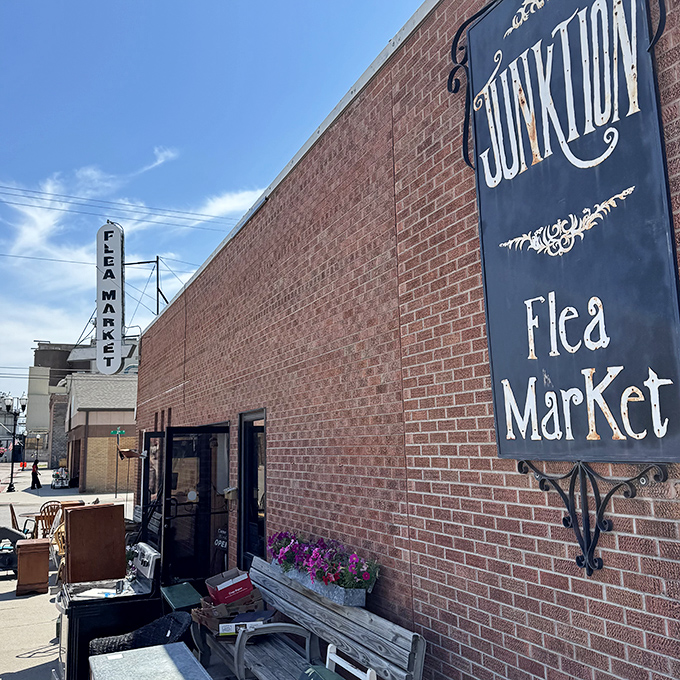 The welcoming exterior of Junktion Flea Market, where that elegant sign and brick facade promise adventures in antiquing for those brave enough to enter.