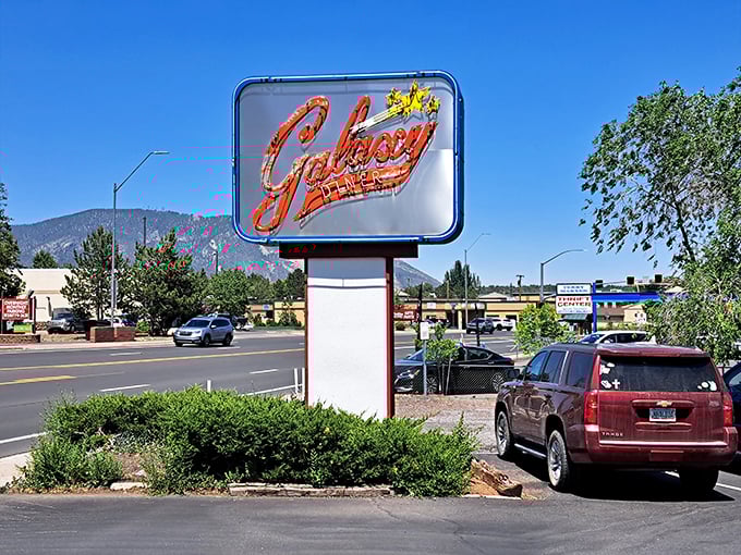 The sign stands sentinel against the mountain backdrop, like a mid-century modern lighthouse guiding hungry travelers to safe harbor. Those peaks aren't just scenery&mdash;they're the audience.
