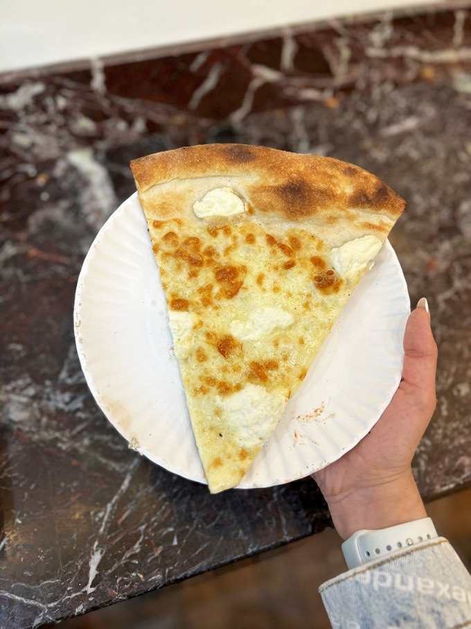 The white pizza slice—a cheese lover's dream that makes you question why tomato sauce ever needed to exist in the first place.